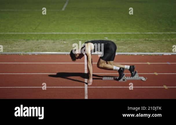 Strong Young Man Starting a Race From Track Starting Blocks Position on ...