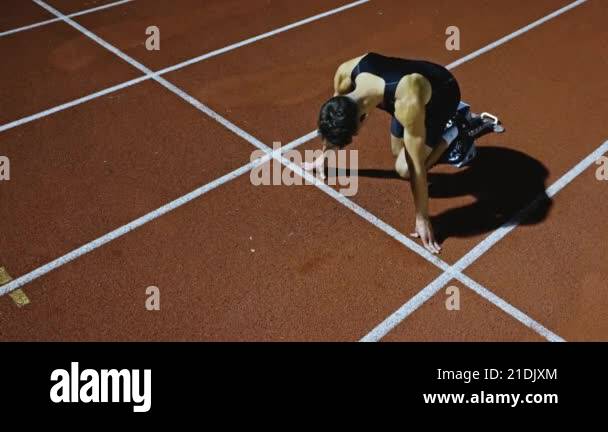 Strong Young Man Starting a Race From Track Starting Blocks Position on ...