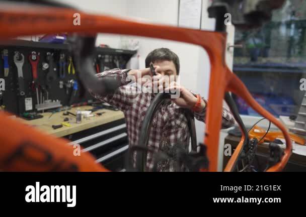 Male bicycle mechanic carefully replacing road bike tire on high ...