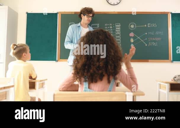 Back view of african girl raised hand while walking in front of class. Skilled male instructor ...