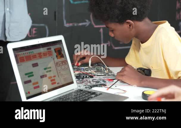 Cute african boy learning to use electronic tool while laptop display ...