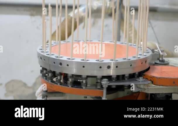 A machine processes wooden dowels, arranging them vertically in a ...