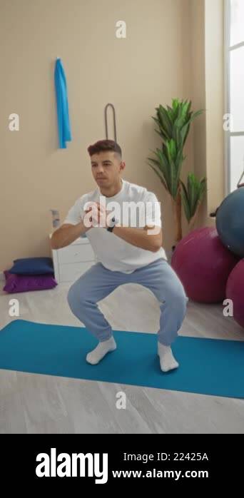Young man exercising indoors at a gym with yoga mat and fitness ...