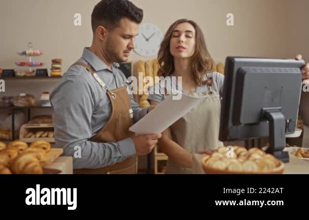Man and woman bakers in a bakery interior analyzing paperwork together ...