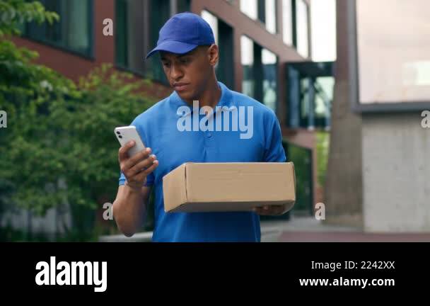 African American courier man confused look at mobile phone GPS map ...