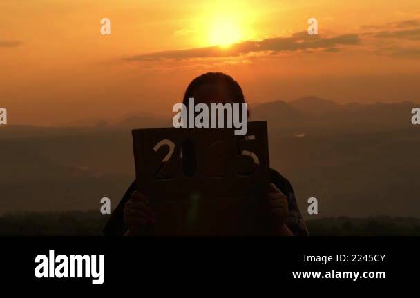 Silhouette of woman hand holding 2025 sign on sunset background. Happy ...
