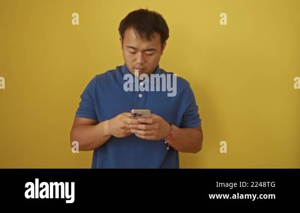Young chinese man using smartphone pointing with finger to you in a ...