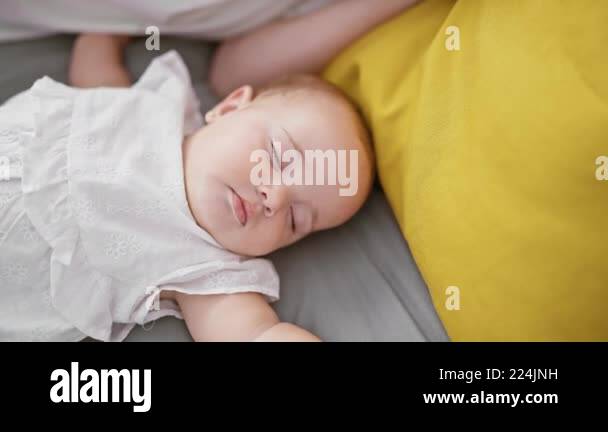 Mother and daughter sharing a loving moment lying together on bed, sleeping in the warm comfort ...