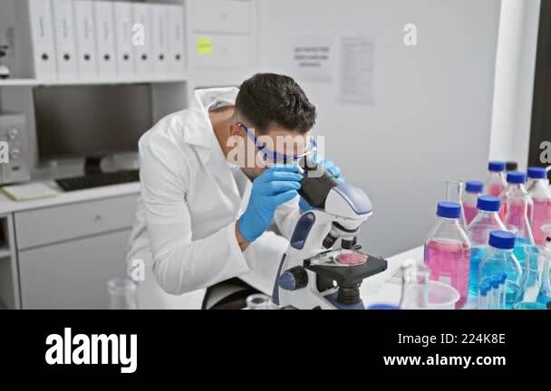 Young scientist man examines specimens under microscope in modern ...
