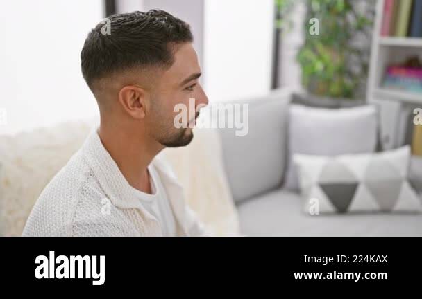Confident young arab man in his natural pose sitting at home on the ...