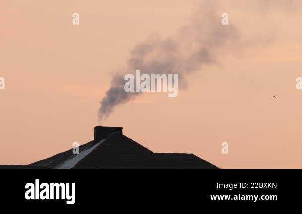 Smoke or vapor rising up from the chimney of a house in early morning ...
