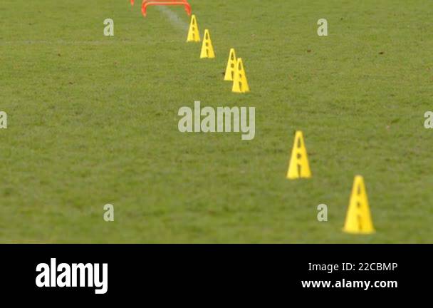 The training setup features bright yellow cones and hurdles arranged on ...