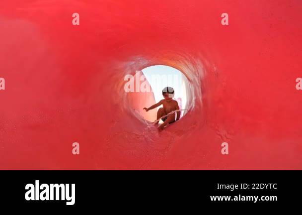 Joyful moments captured as a young boy slides down a vibrant red water ...