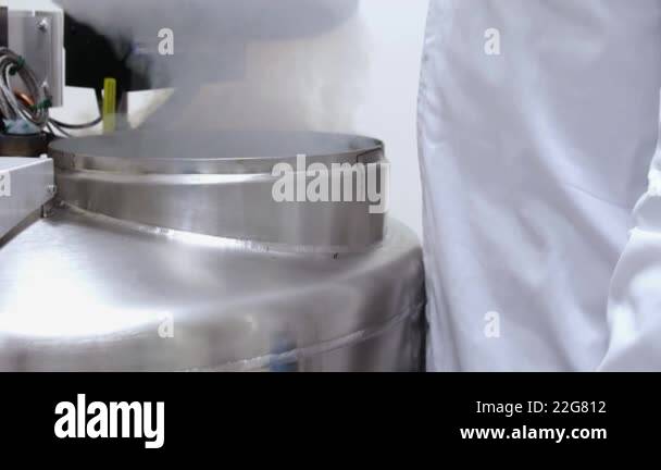 Precise laboratory technician carefully opening cryogenic storage tank ...