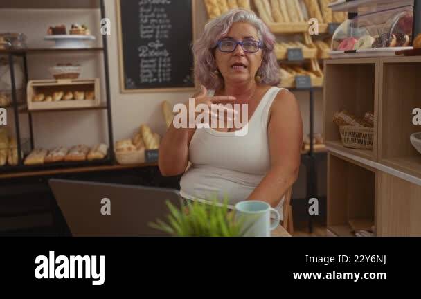 Woman talking in a bakery with bread shelves in background, elderly ...