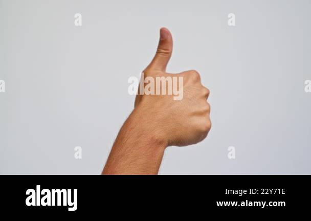Thumbs up gesture by a man's hand with a neutral background showing ...