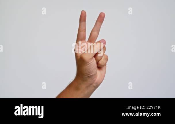 Hand gesture by man showing victory sign against plain background Stock ...