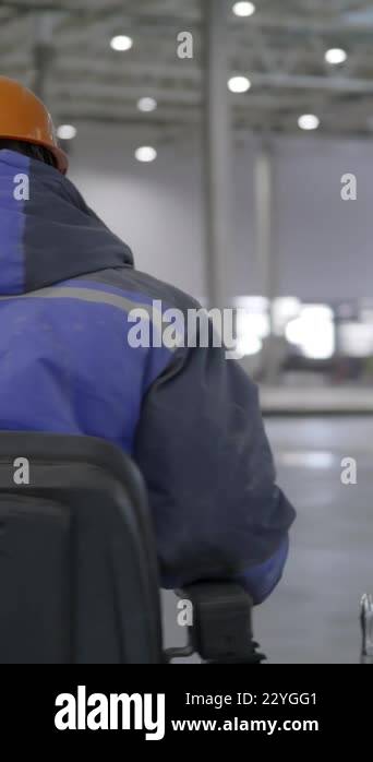 An industrial worker expertly operating a machine in a large warehouse ...