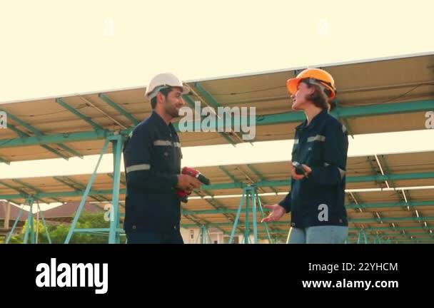 Male electrical engineer and female worker walk talk consult and shake ...