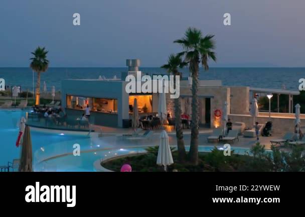 Evening view of Portes Lithos Luxury Resort with illuminated pool, palm ...