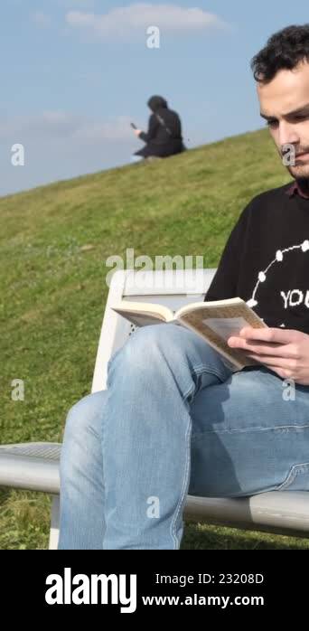 Image of lonely man reading novel on white bench in sunny day ...