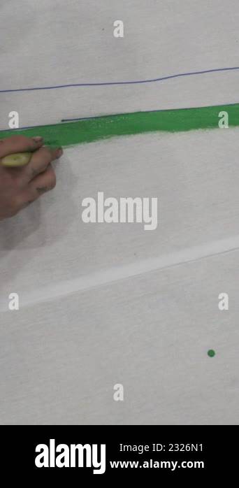 A hand distributing the green paint with a brush around a straight line ...