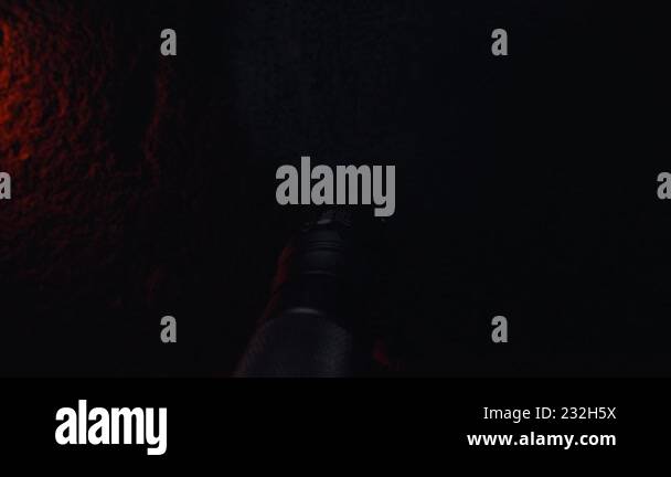 A close-up view of a flashlight illuminating a dark, textured surface ...