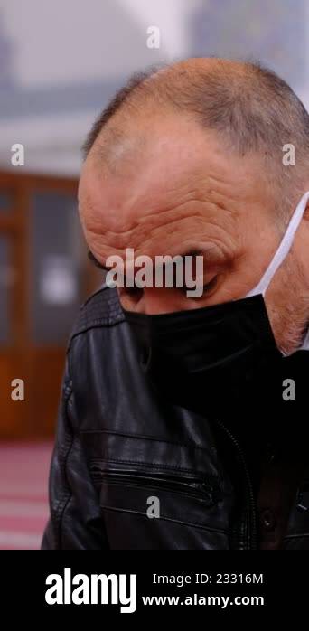 Close-up of a man with a black mask on his face praying in a mosque ...
