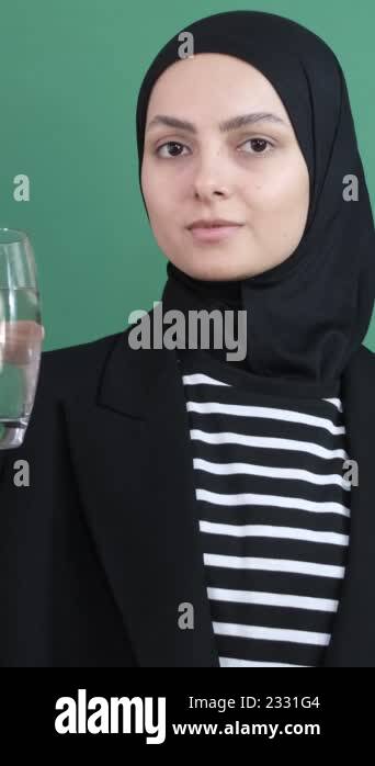 Muslim woman drinking water, girl sign water in front of green screen ...