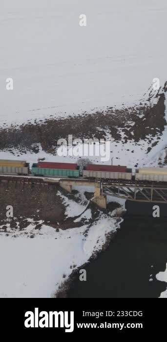 aerial view of freight train crosses the bridge on a snowy winter day ...