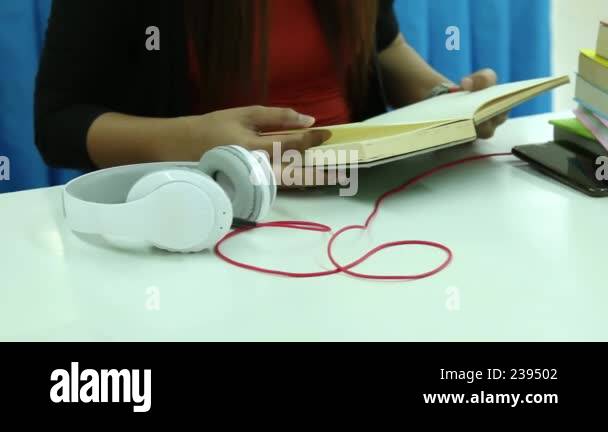 Woman holding and reading open book on white desk, with white ...