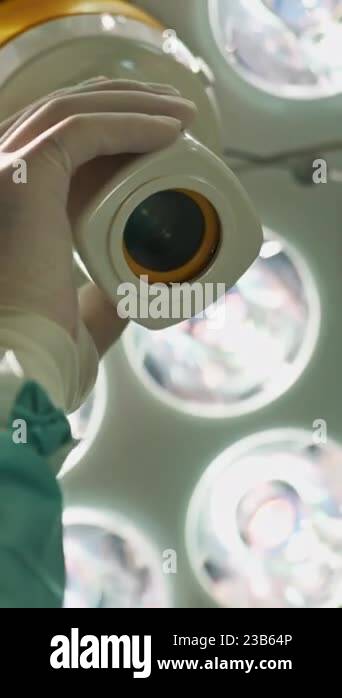 Vertical Screen: Close-up of surgeons gloved hand adjusting a medical ...