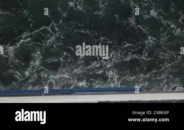 view of a boat passing the ocean with white foam from water waves ...
