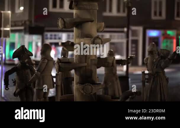 A group of statues are gathered around a fountain, with one statue of a ...