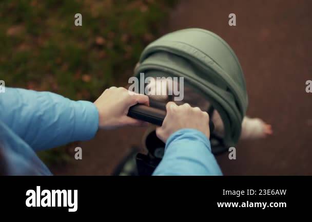 A close-up of the hands of a mother carrying a stroller with a baby in ...