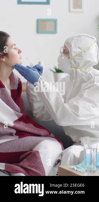 Vertical shot of sick female patient sitting on couch at home while ...