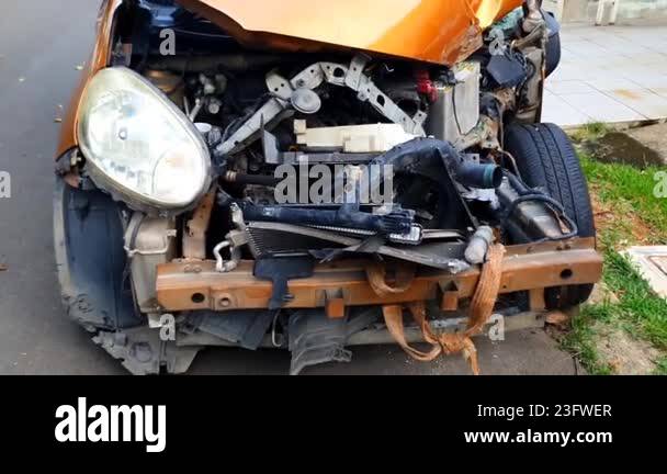 A heavily damaged orange car with a crumpled front end, shattered ...