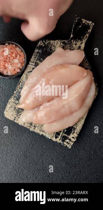 Raw chicken fillet cut into strips with spices and herbs on a wooden ...
