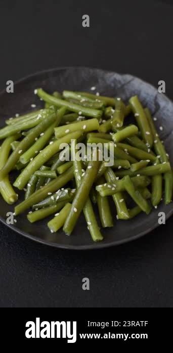 Steamed green beans on a plate with olive oil, sesame seeds, salt and ...