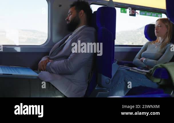 On a pleasant train ride, a welldressed man relaxes while a woman ...