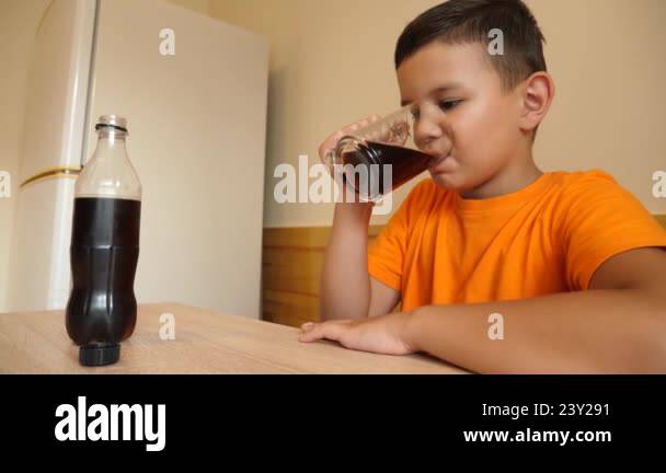 A boy drinks soda from a glass while sitting at the table Stock Video ...