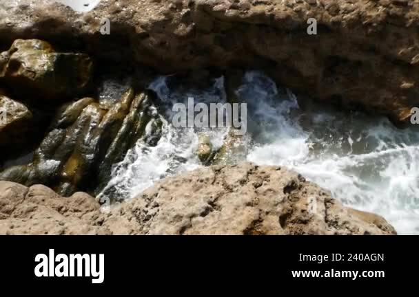 Rocks on the coast with a small wave gently flowing between the stones ...