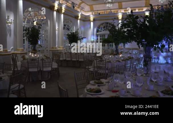 A luxurious banquet hall with high ceilings, gold and white detailing ...
