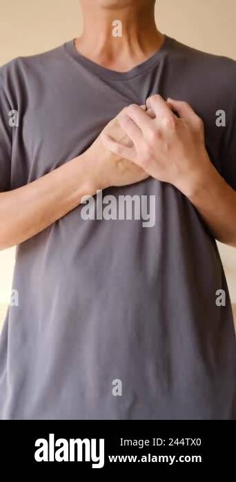 A person in a gray shirt pressing both hands to their chest, depicting ...