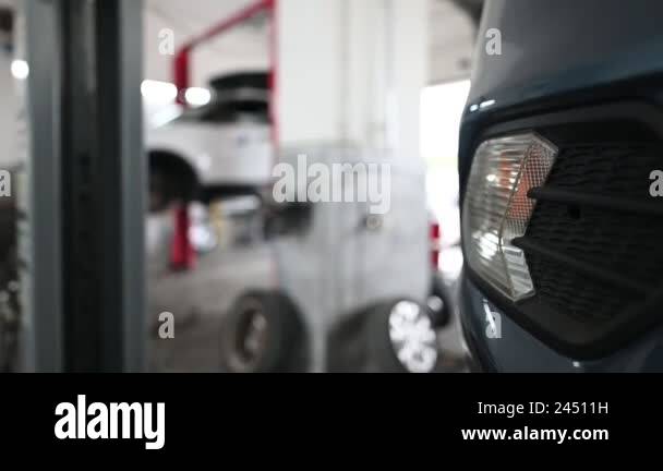 A blue car in for a service or repair in a busy automotive garage with ...