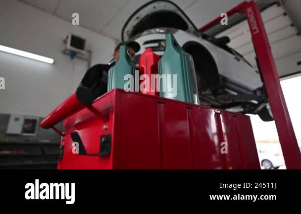 Oil containers in focus, car in the background on a hydraulic ramp ...