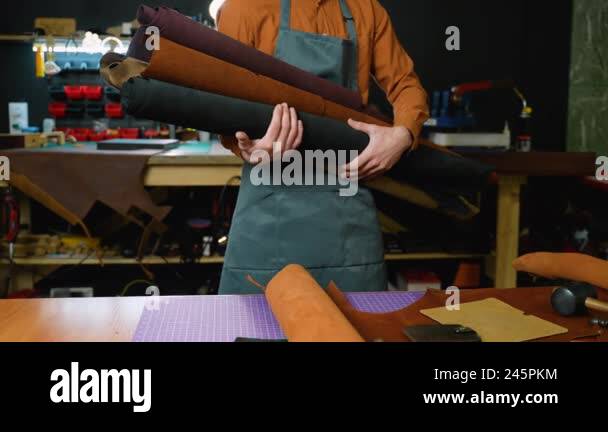 Skilled craftsman holding a roll of high-quality leather, preparing ...