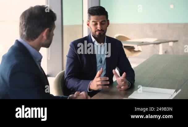Happy handsome Indian businessman talking to male business partner ...