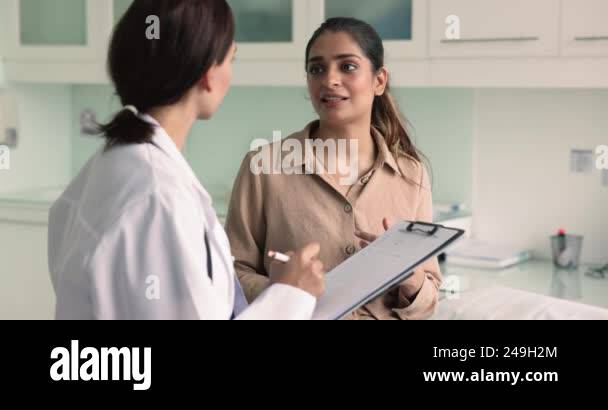 Young Indian patient woman telling doctor about illness symptoms ...