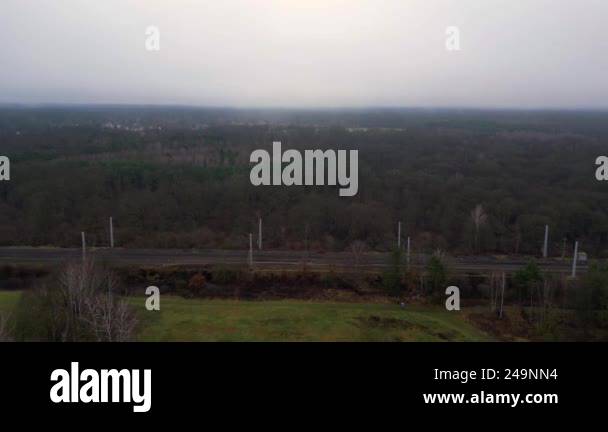 Aerial view of railroad crossing large forest under overcast sky ...